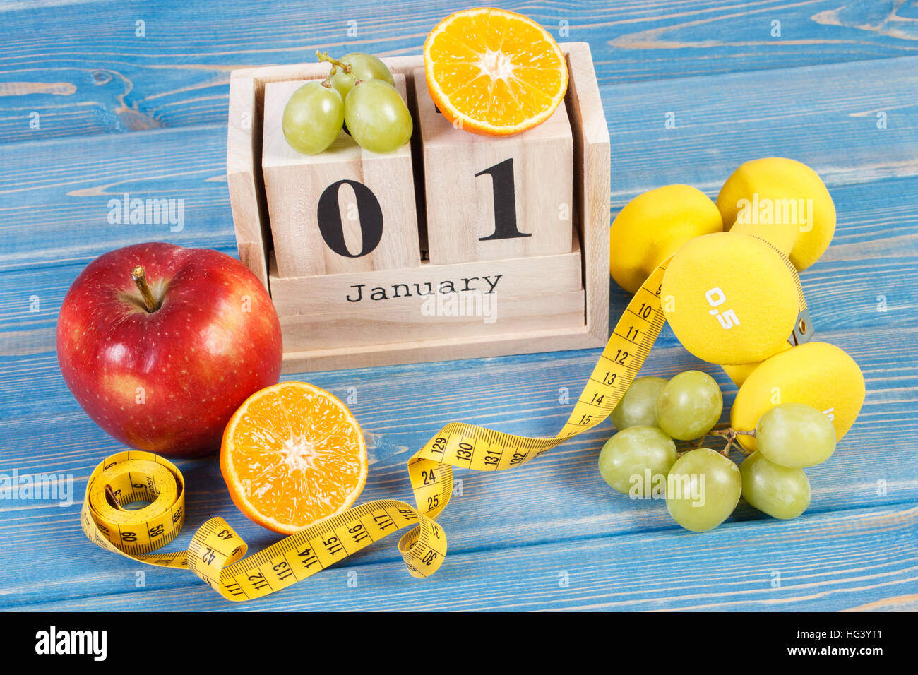 January 1 on cube calendar, fresh fruits, dumbbells and tape measure ...