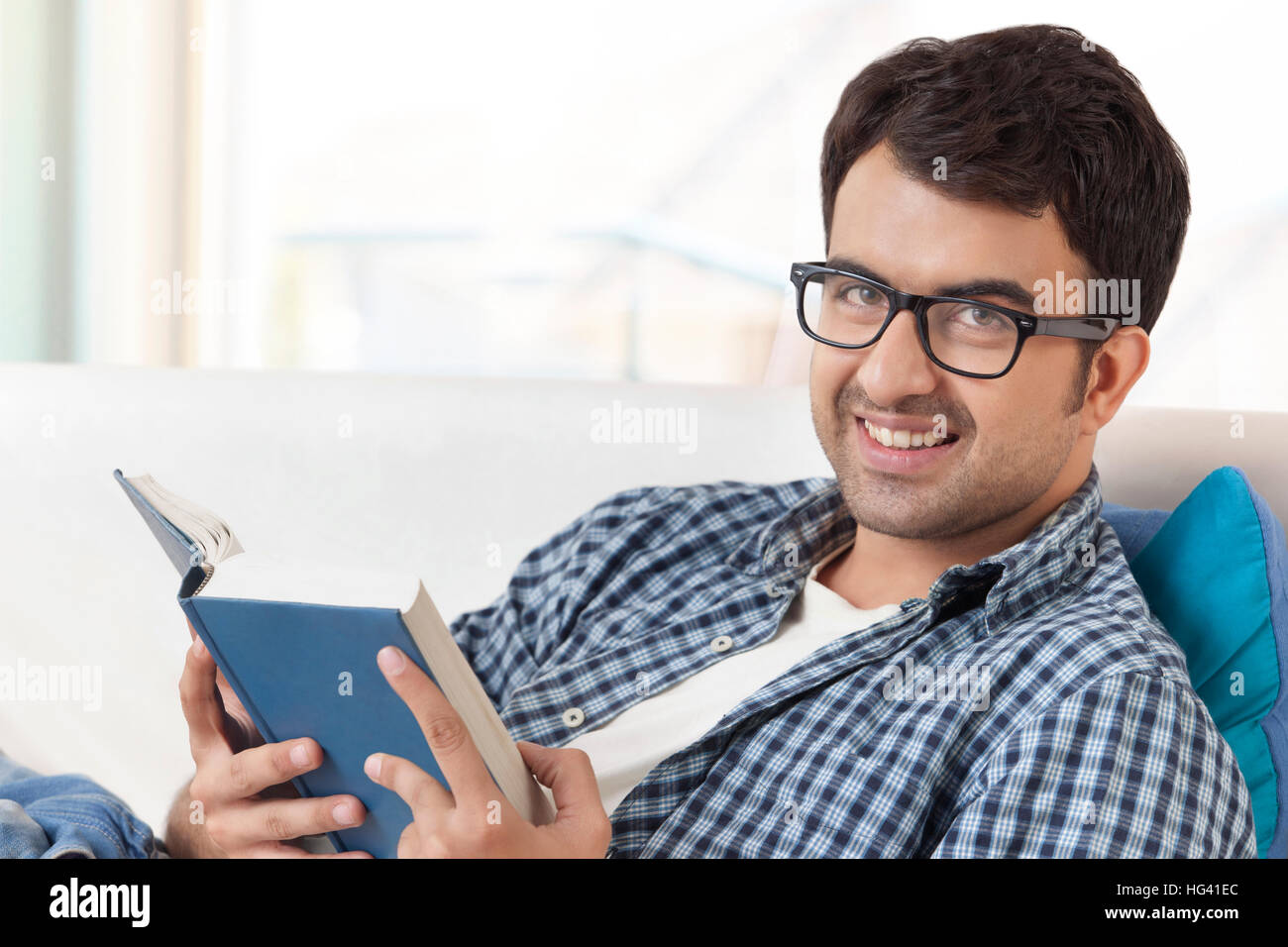 Smiling young man reading book Stock Photo - Alamy