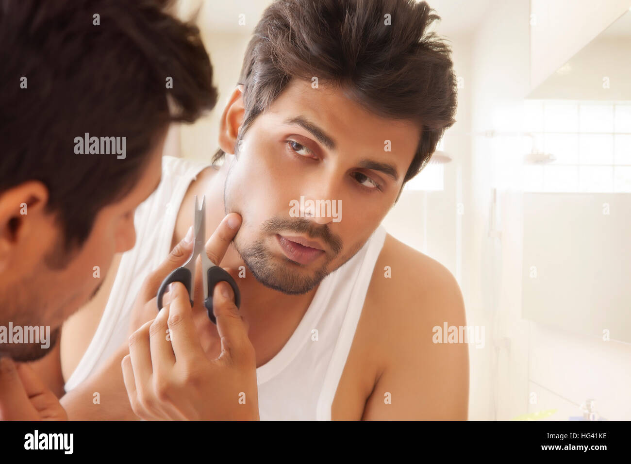 Man grooming his beard with scissors Stock Photo - Alamy