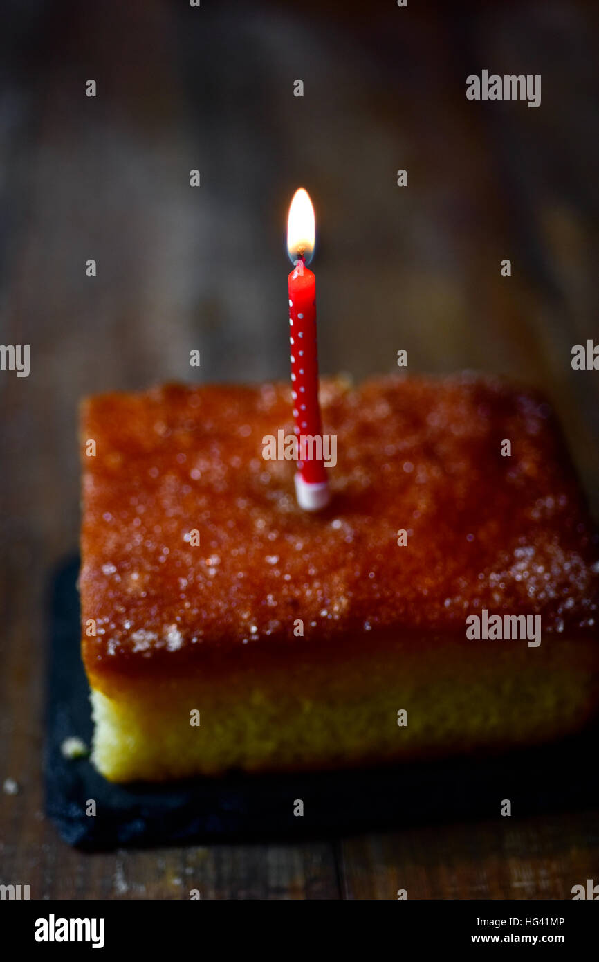 closeup of a cake topped with a lit birthday candle on a rustic wooden ...