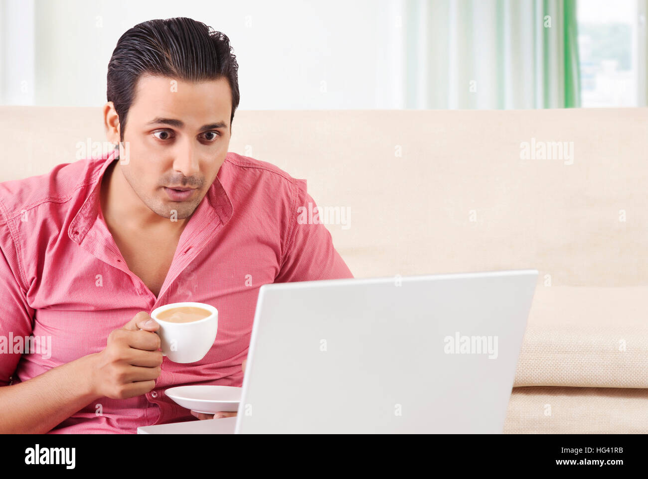 Young man drinking tea while using laptop Stock Photo - Alamy
