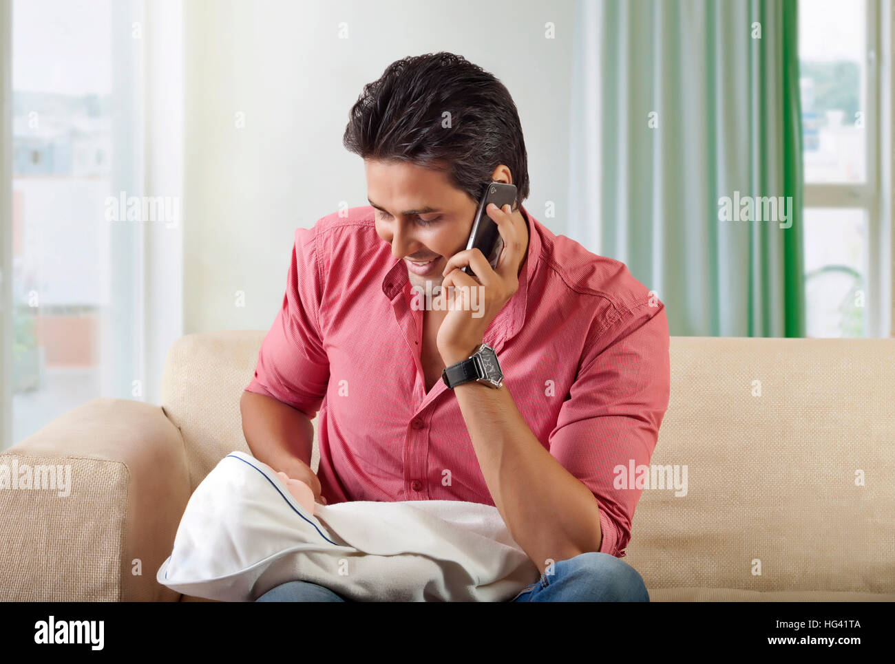 Smiling father holding baby and talking on phone Stock Photo - Alamy