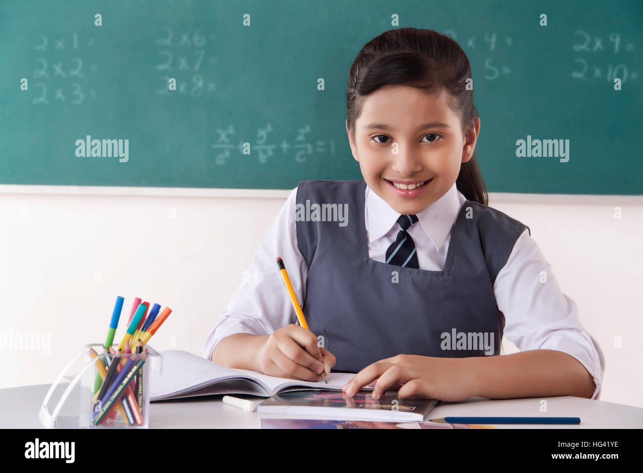Girl smiling writing notes in a classroom Stock Photo - Alamy