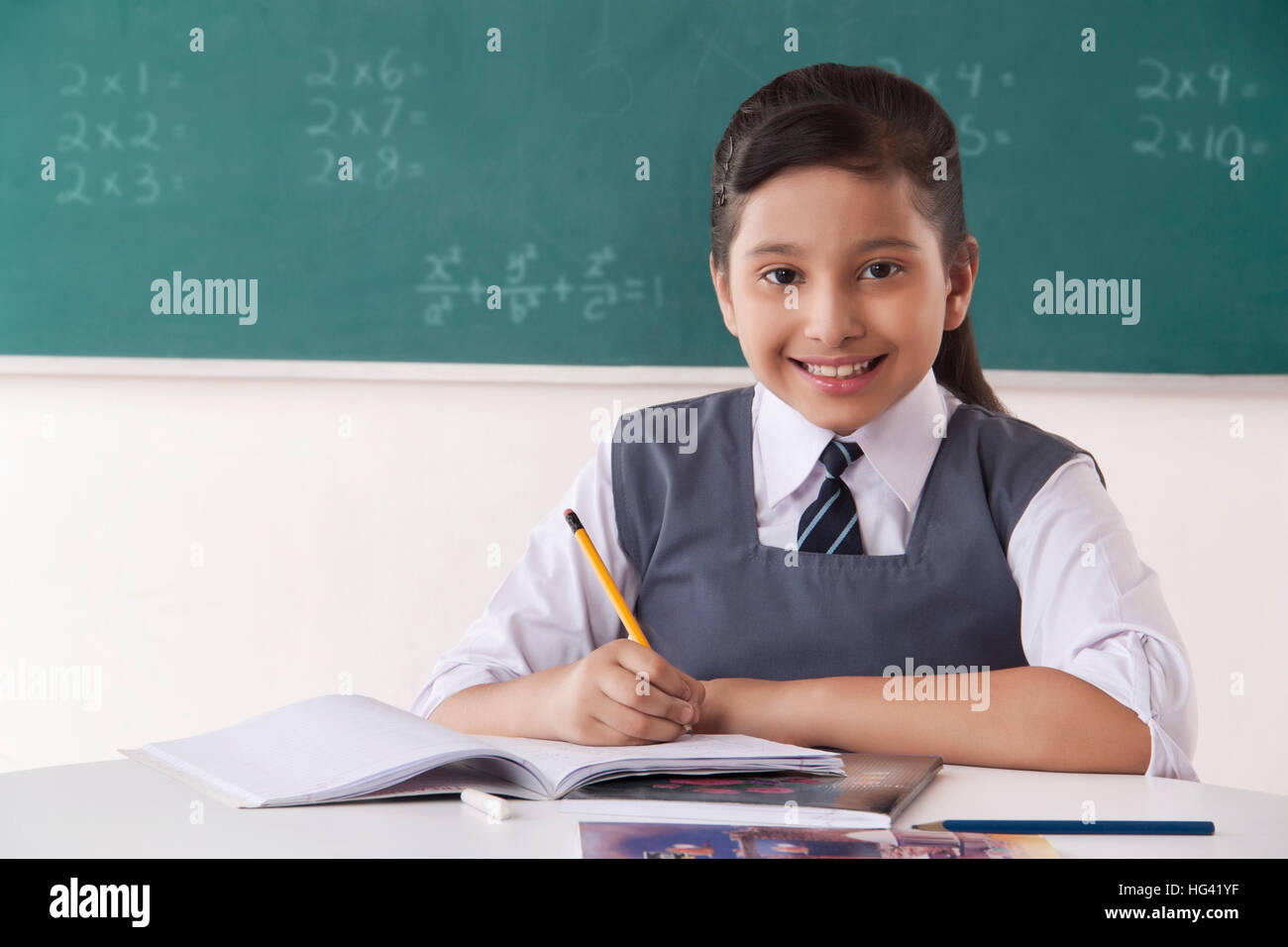 Smiling girl writing notes in a classroom Stock Photo - Alamy