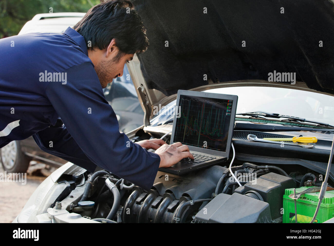 Mechanic using laptop while repairing car engine Stock Photo - Alamy