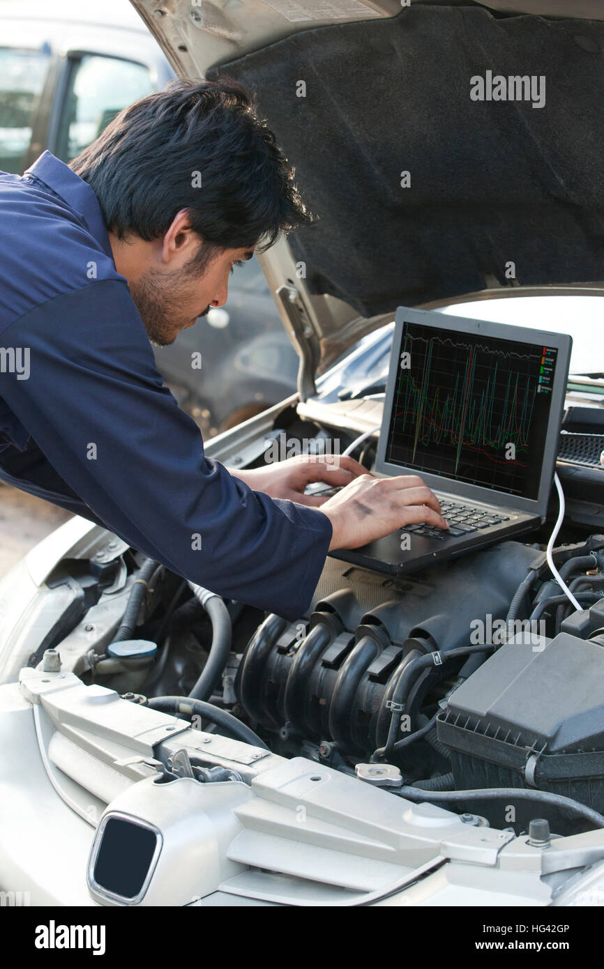 Mechanic using laptop while repairing car engine Stock Photo - Alamy