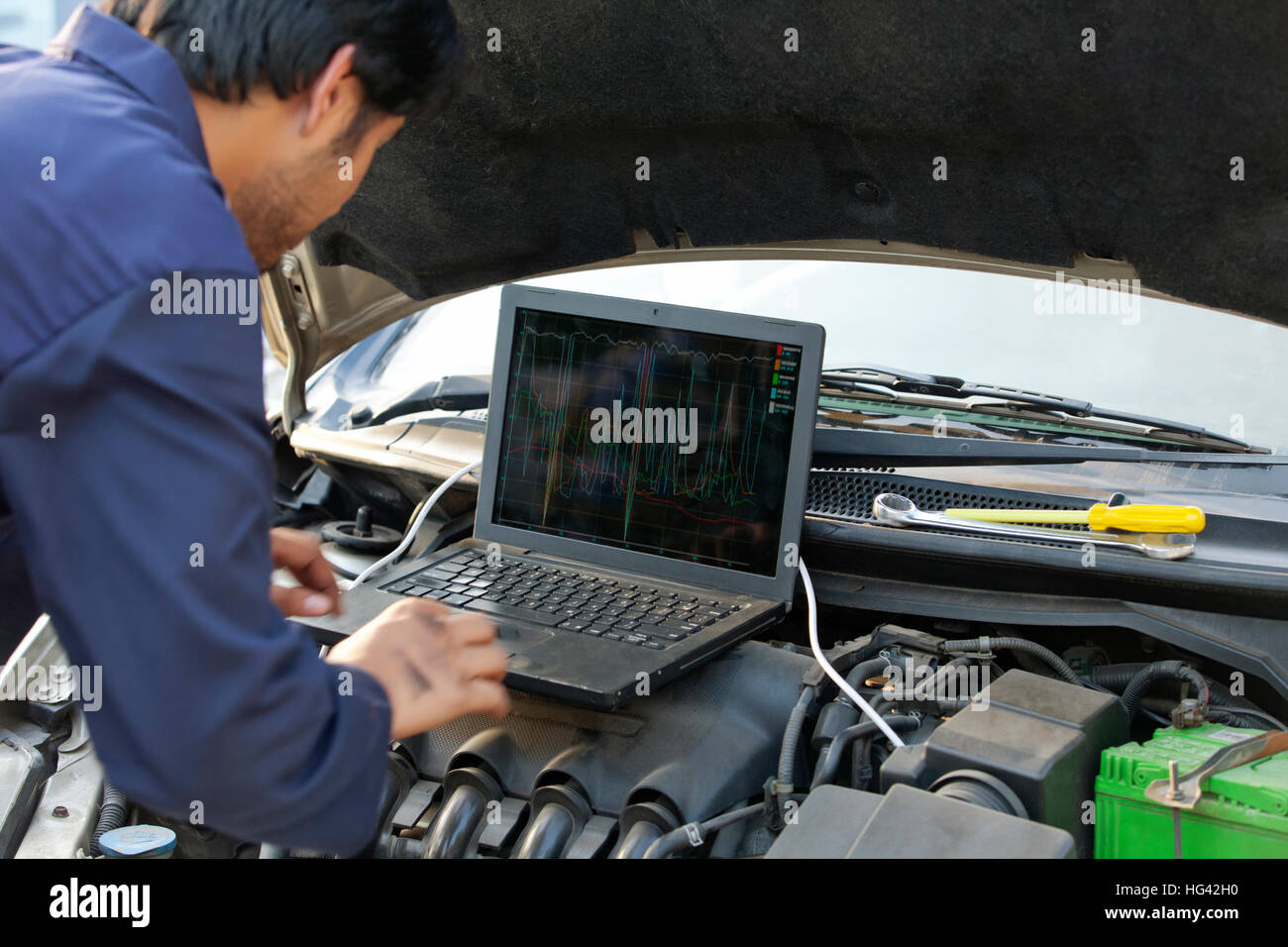 Mechanic using laptop on car engine Stock Photo - Alamy