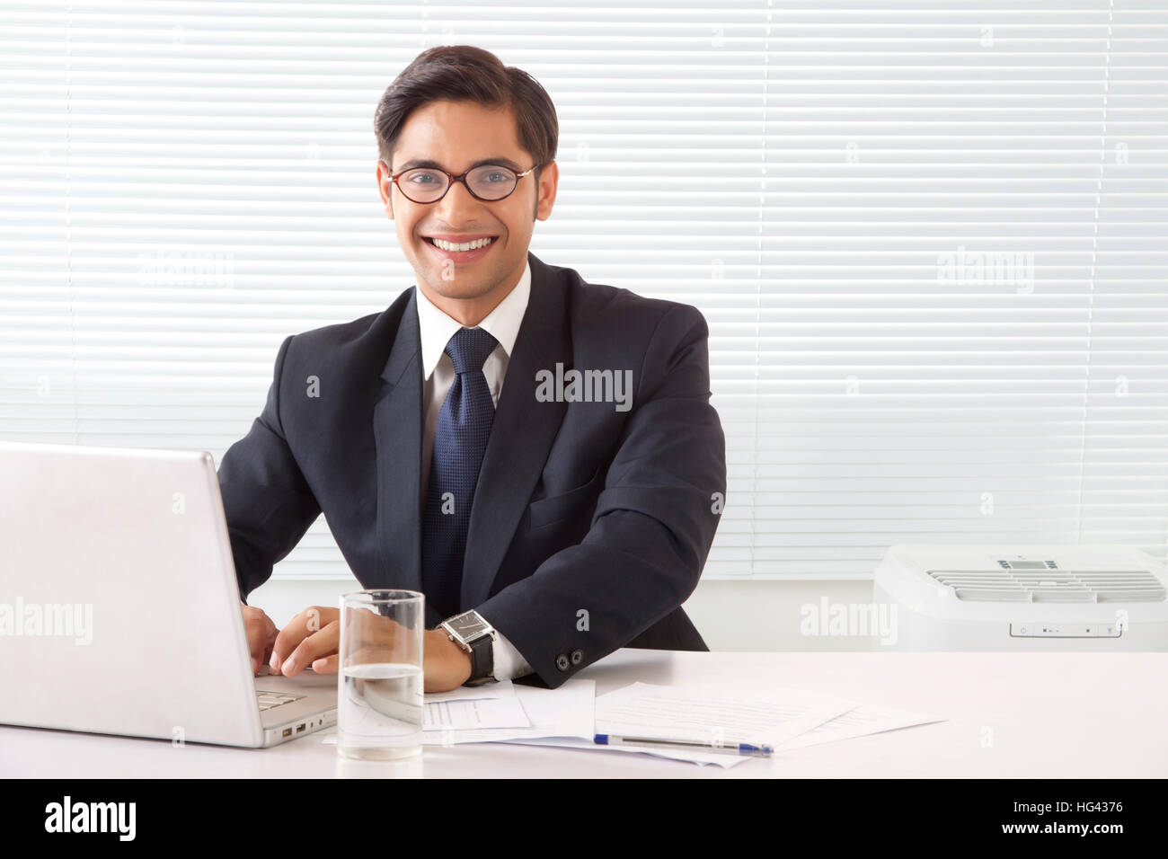 Happy and smiling young professional man working on laptop computer in ...
