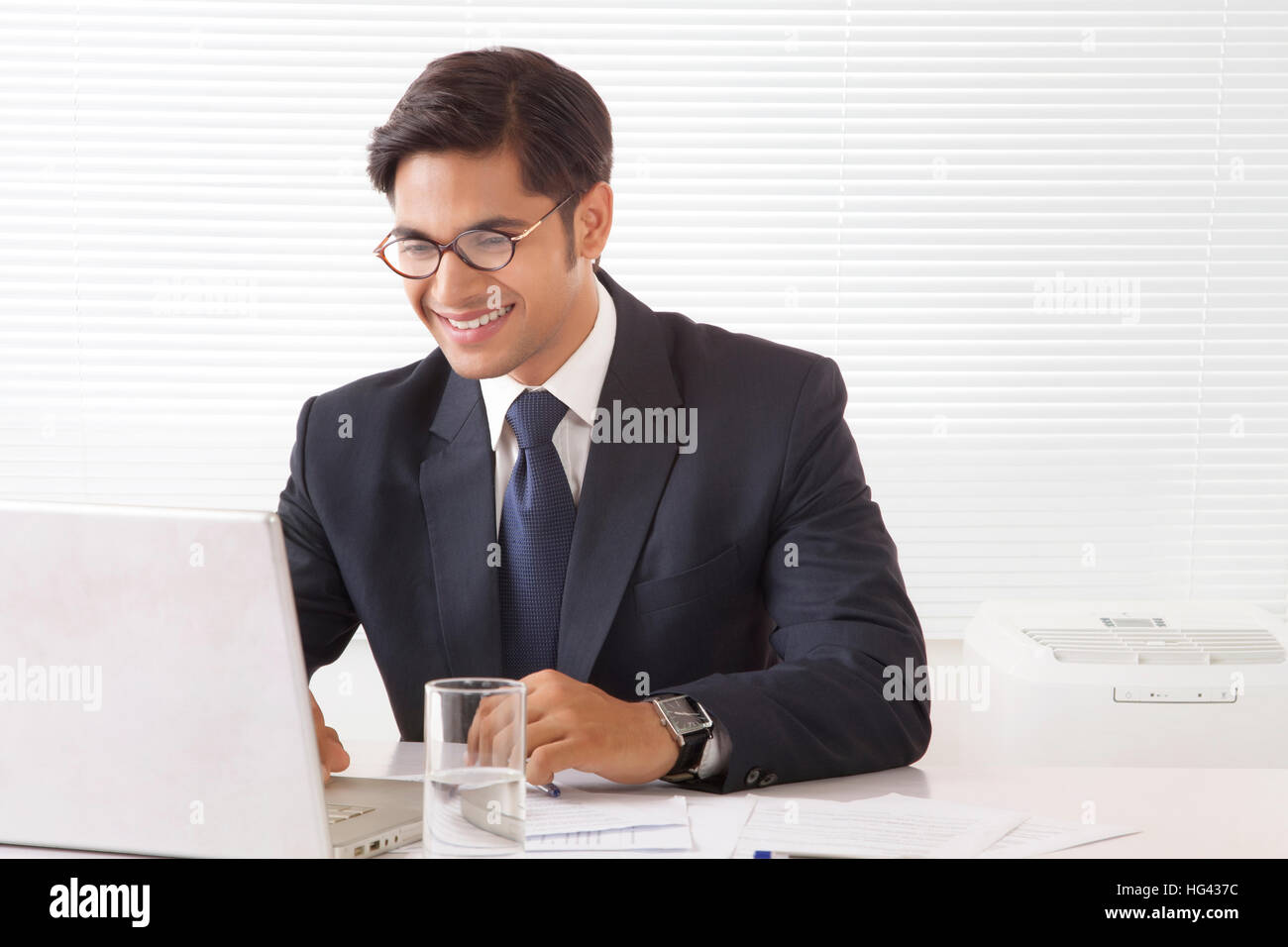 Happy and smiling young professional man working on laptop computer in ...