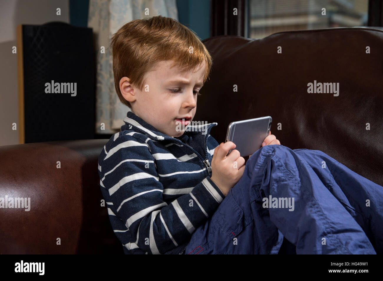 Child using technology. 5 year old boy with a smart phone or iPhone ...