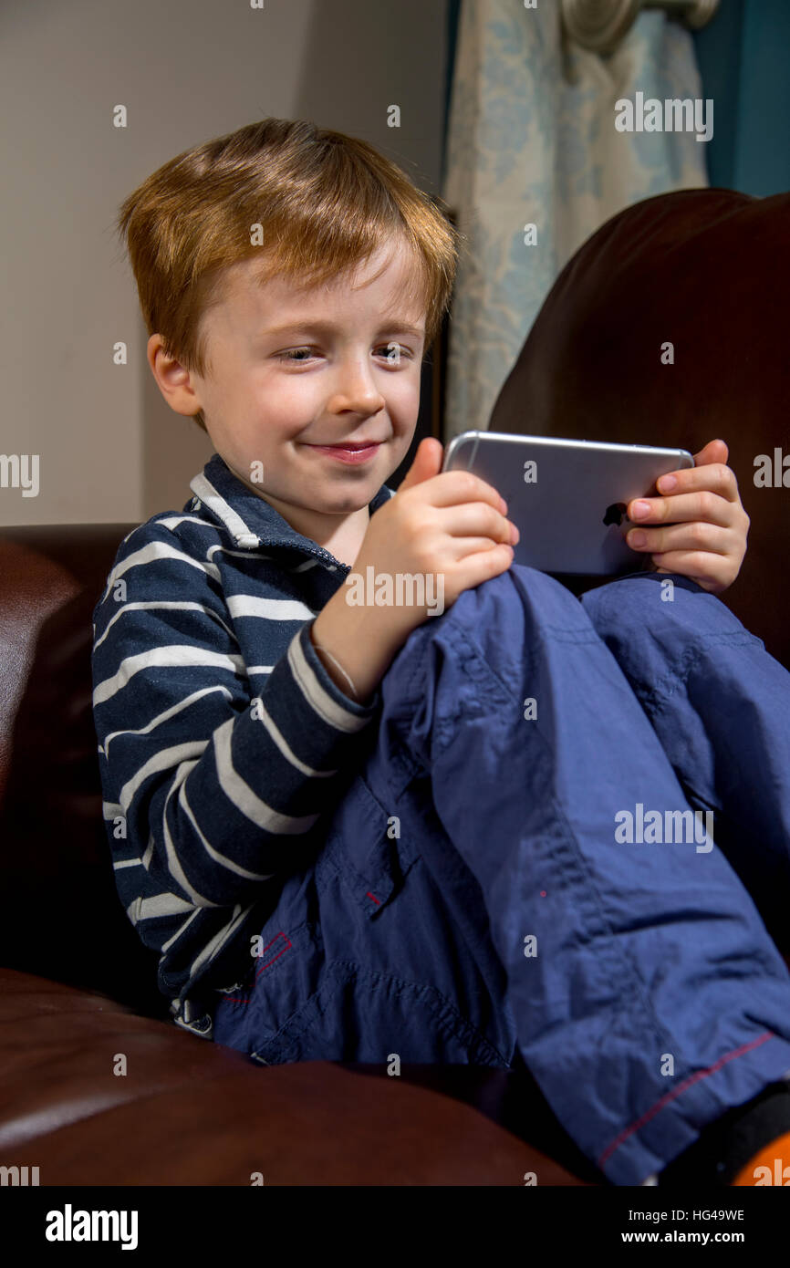Child using technology. 5 year old boy with a smart phone or iPhone ...