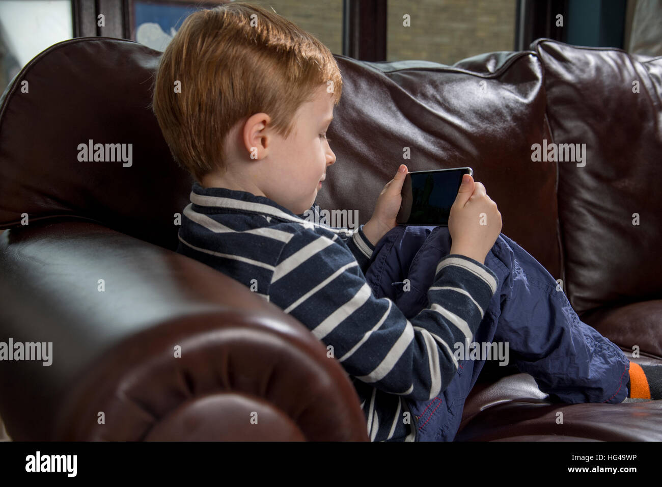 Child using technology. 5 year old boy with a smart phone or iPhone ...