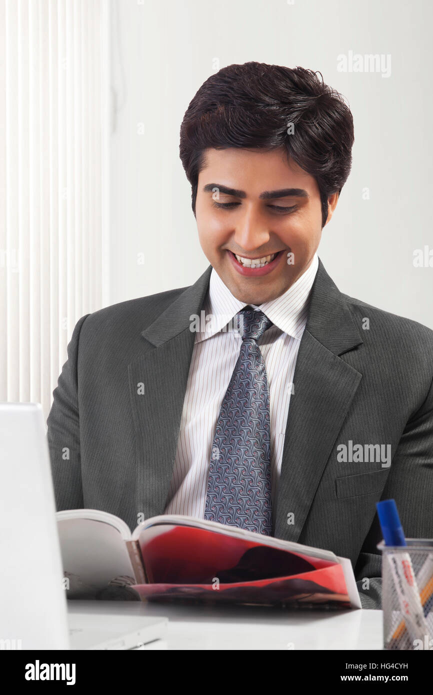 Smiling businessman reading magazine Stock Photo - Alamy