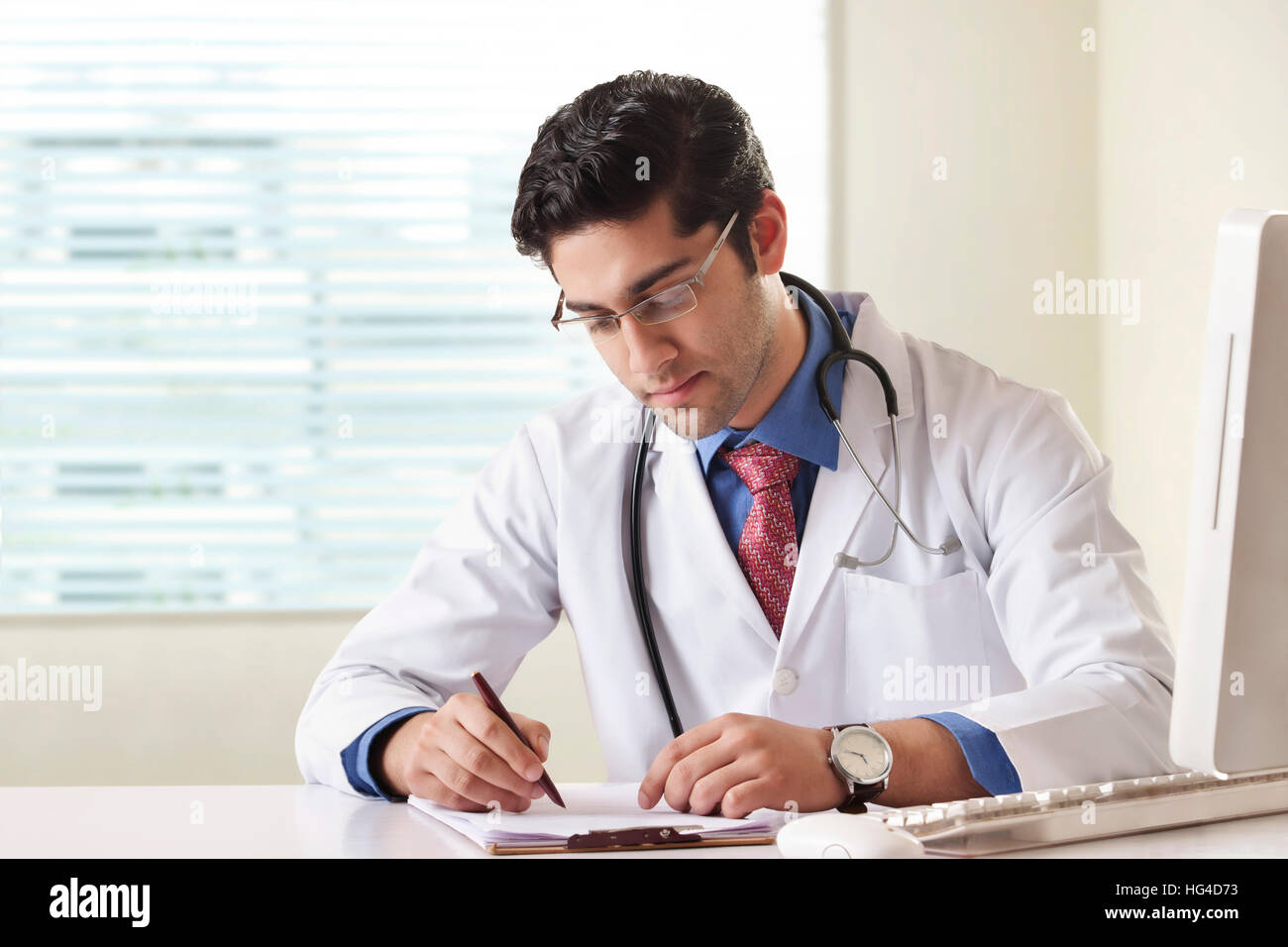 Male doctor sitting at desk Stock Photo - Alamy