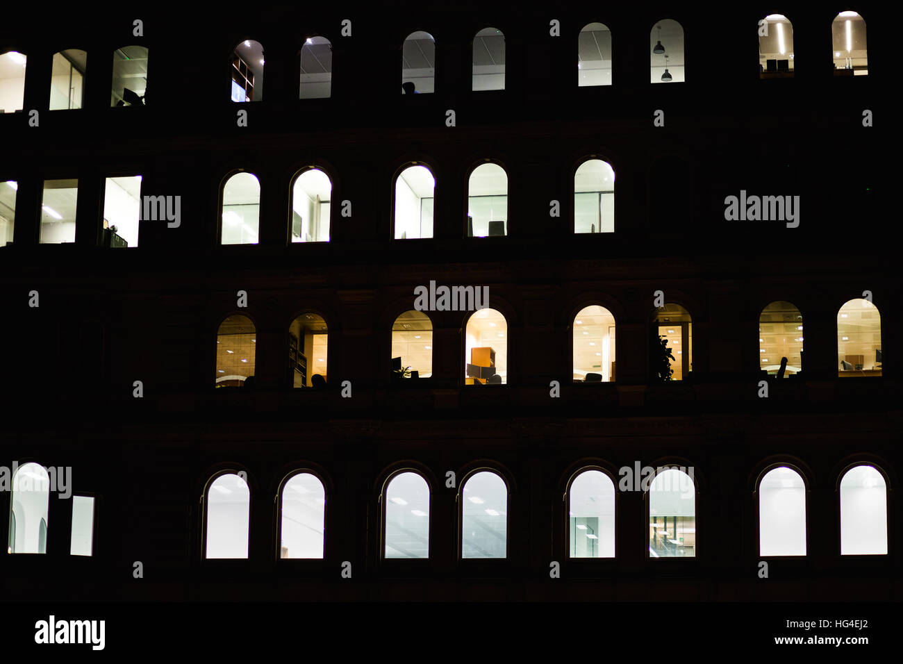 dozens of office building windows shapes illuminated at night closeup ...