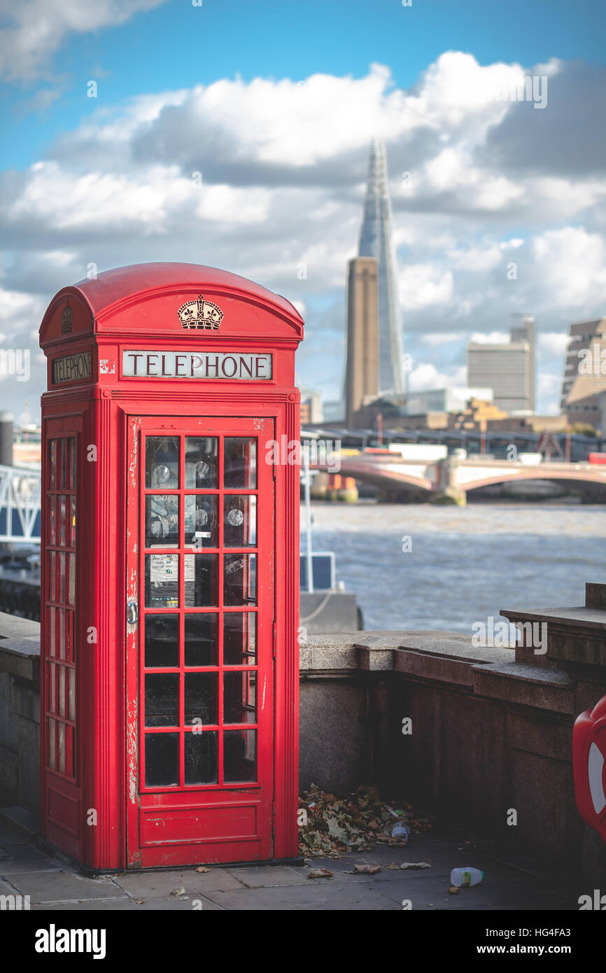 Red telephone cabin on the Thames river in London with skyline in ...