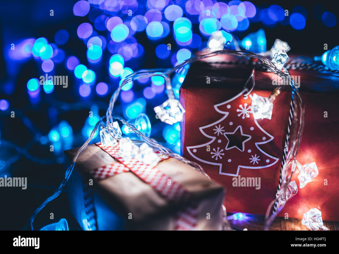 Christmas gift boxes with glowing garland and blue bokeh lights Stock ...