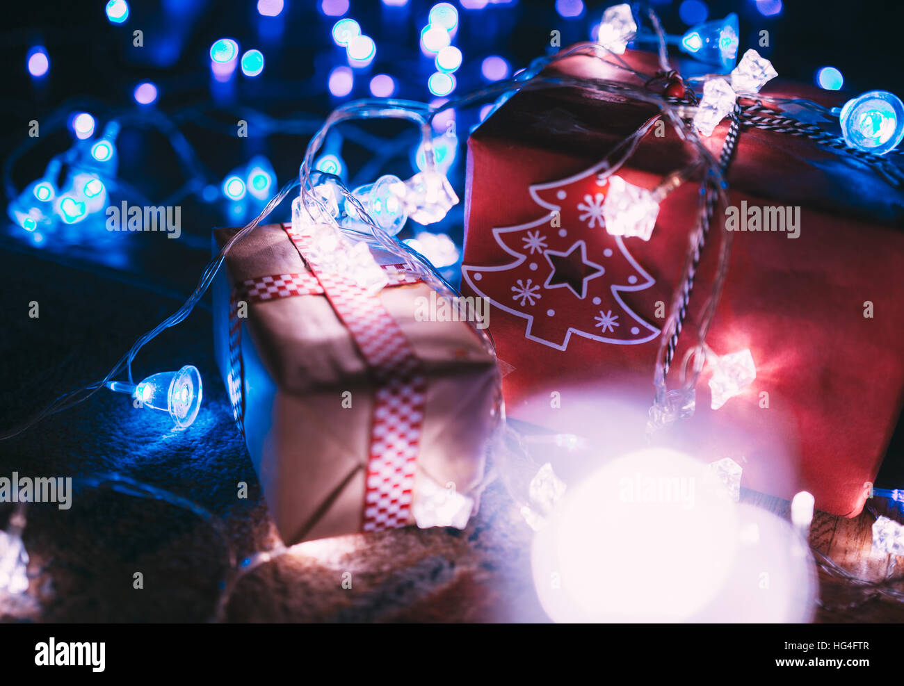 Christmas gift boxes with glowing garland and blue bokeh lights Stock ...