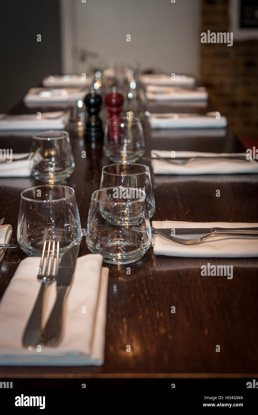 A table laid out ready for lunch with napkins and glasses and cutlery ...