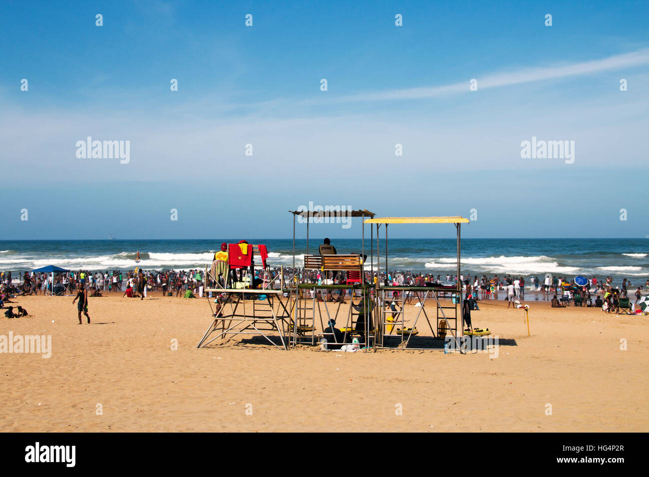 Lifeguards on viewing platform watch over many unknown people on beach ...