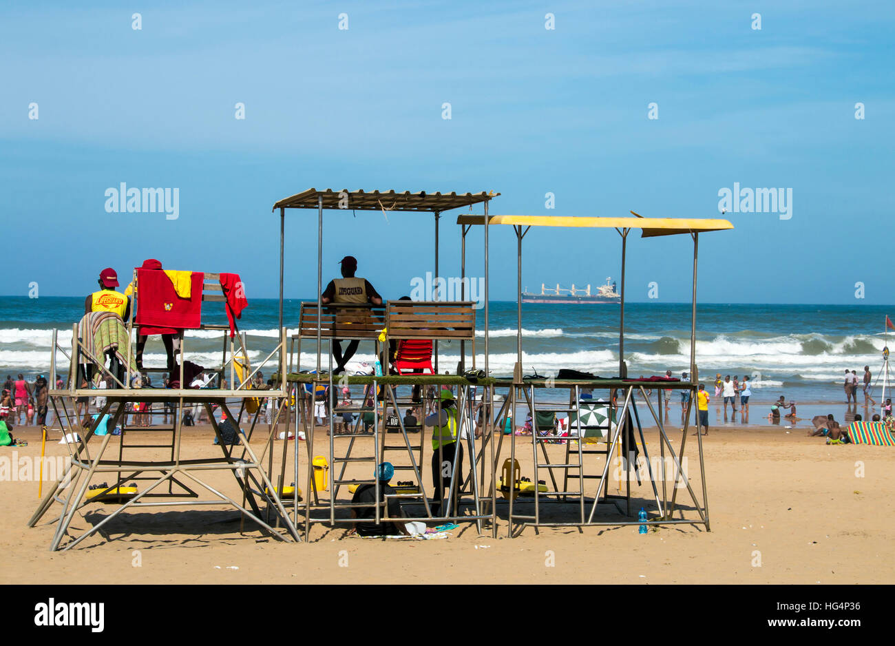 Lifeguards on viewing platform watch over many unknown people on beach ...