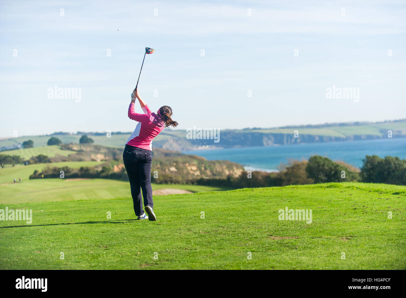 A young female golfer teeing off at the first hole Stock Photo - Alamy