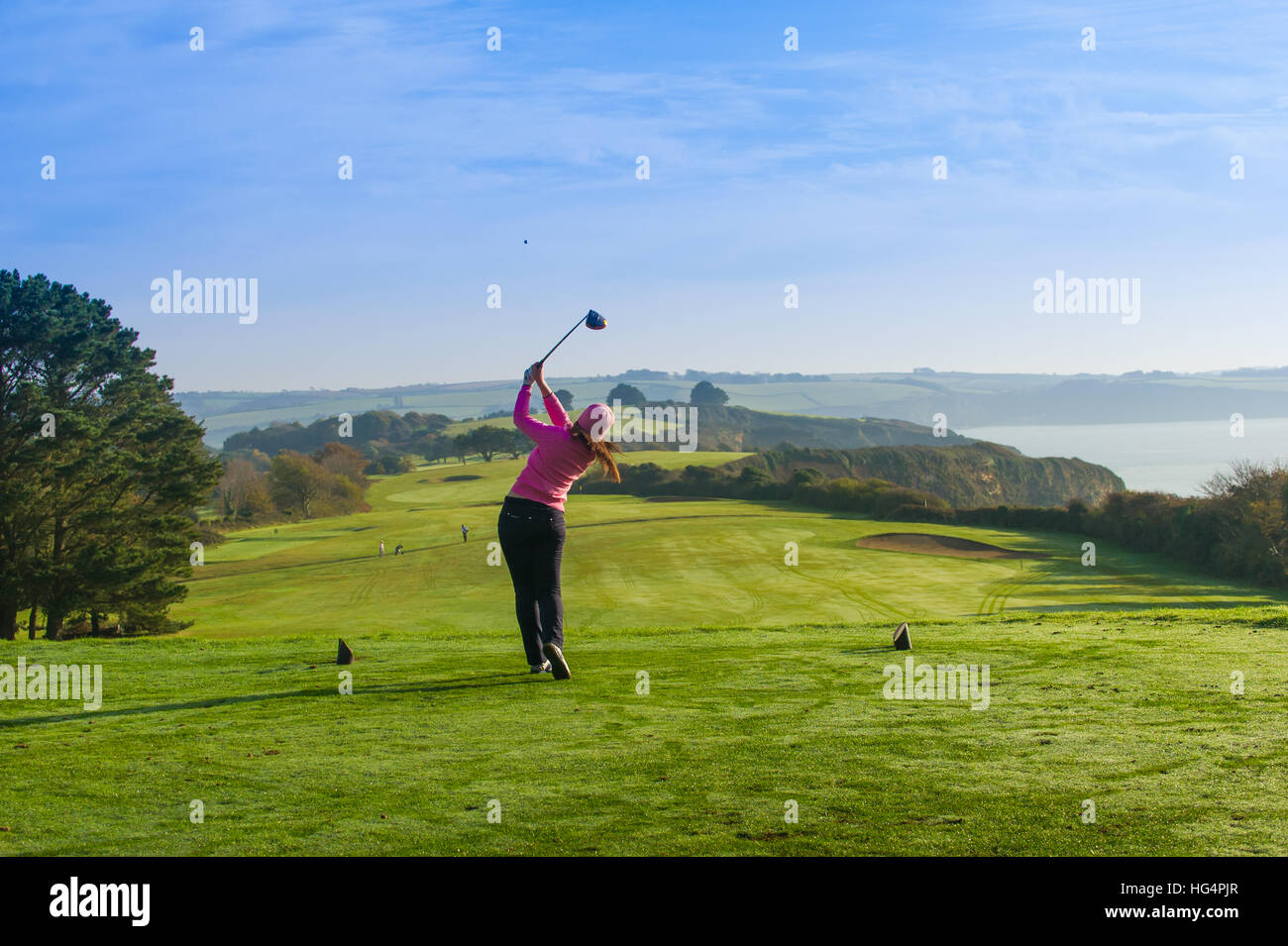 A young female golfer teeing off at the first hole Stock Photo - Alamy