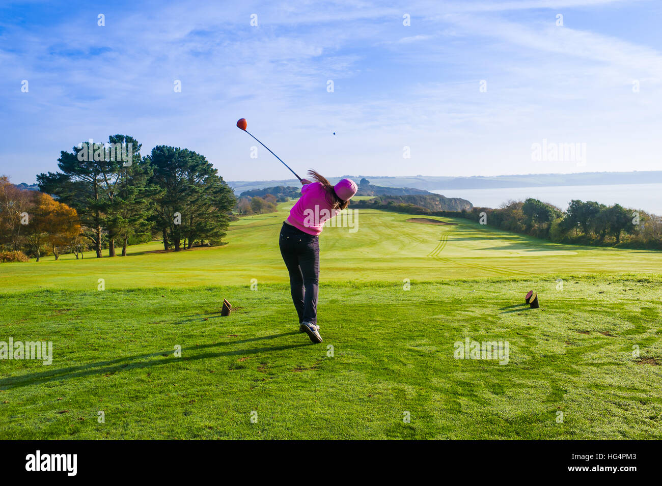 A young female golfer teeing off at the first hole Stock Photo - Alamy
