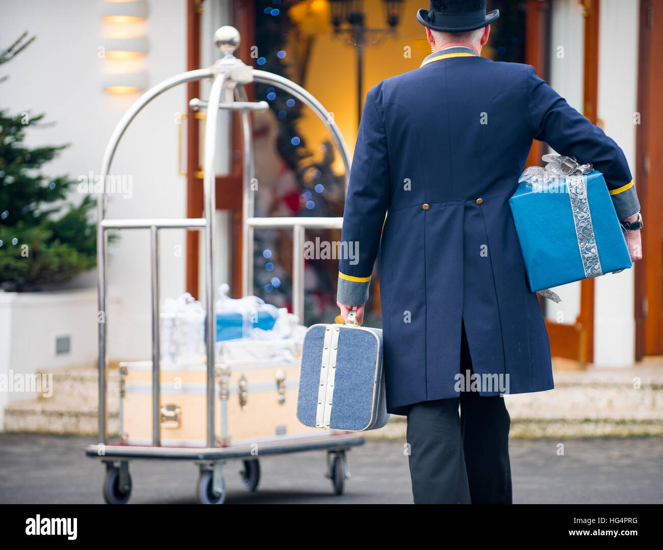 A hotel porter bringing suitcases into a lobby at Christmas Stock Photo ...