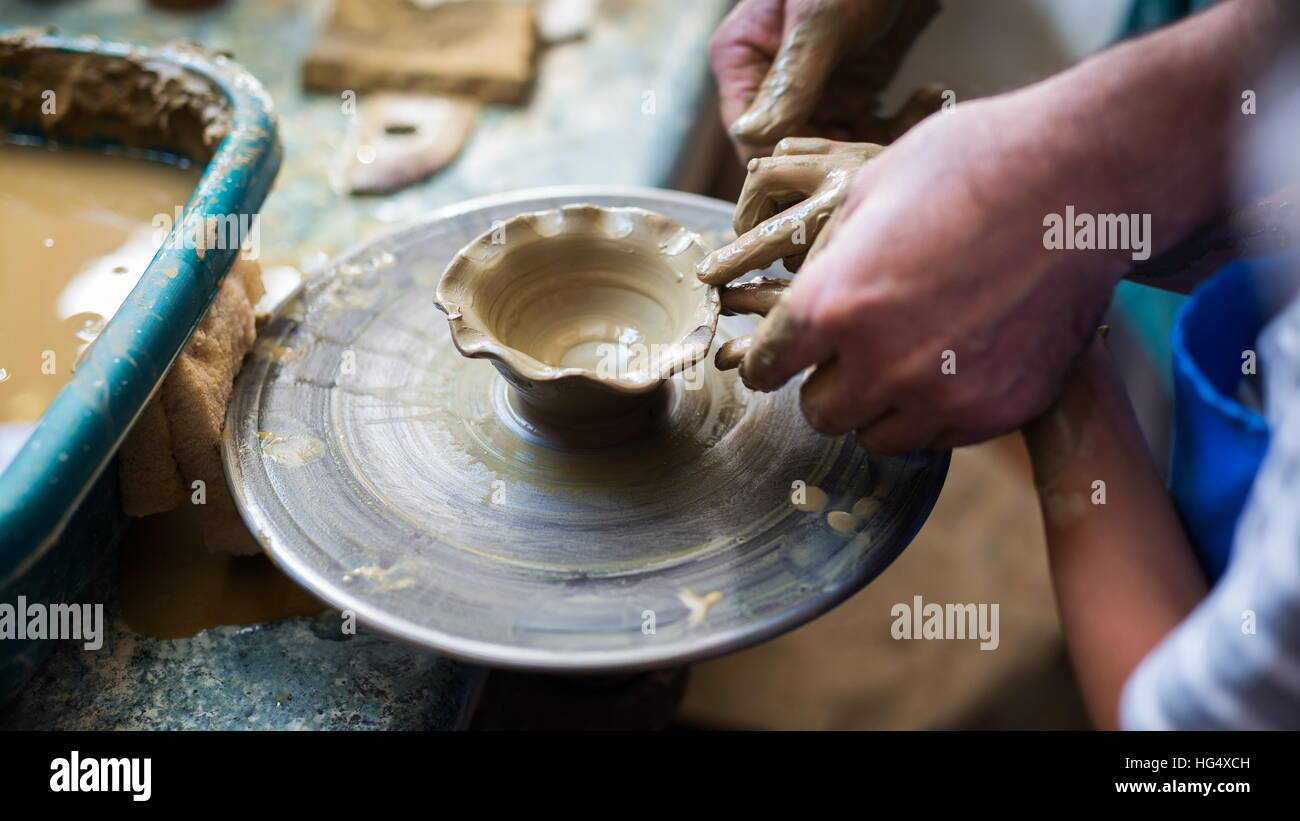 Senior potter teaching a little boy the art of pottery. Child working ...
