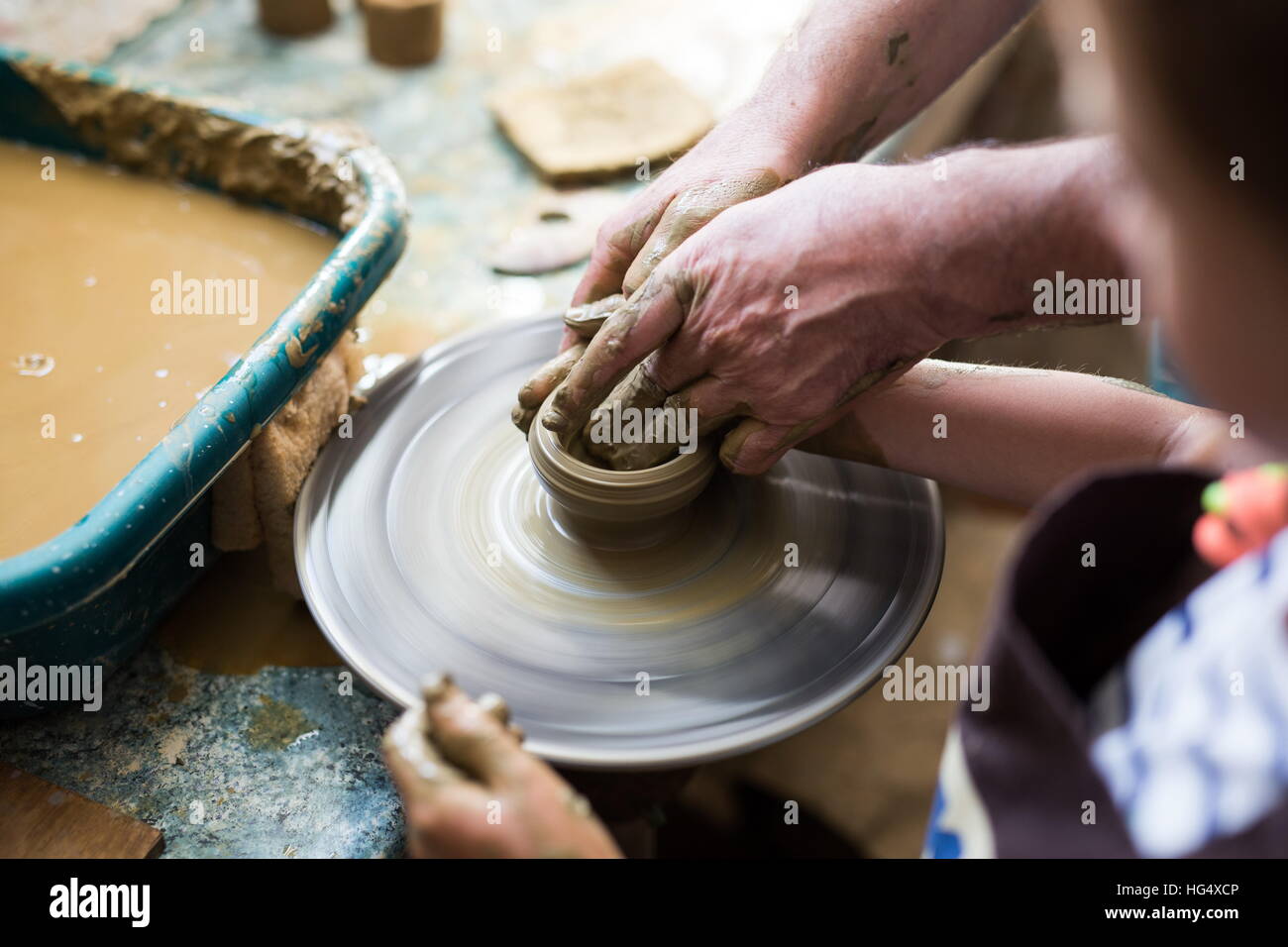 Senior potter teaching a little girl the art of pottery. Child working ...