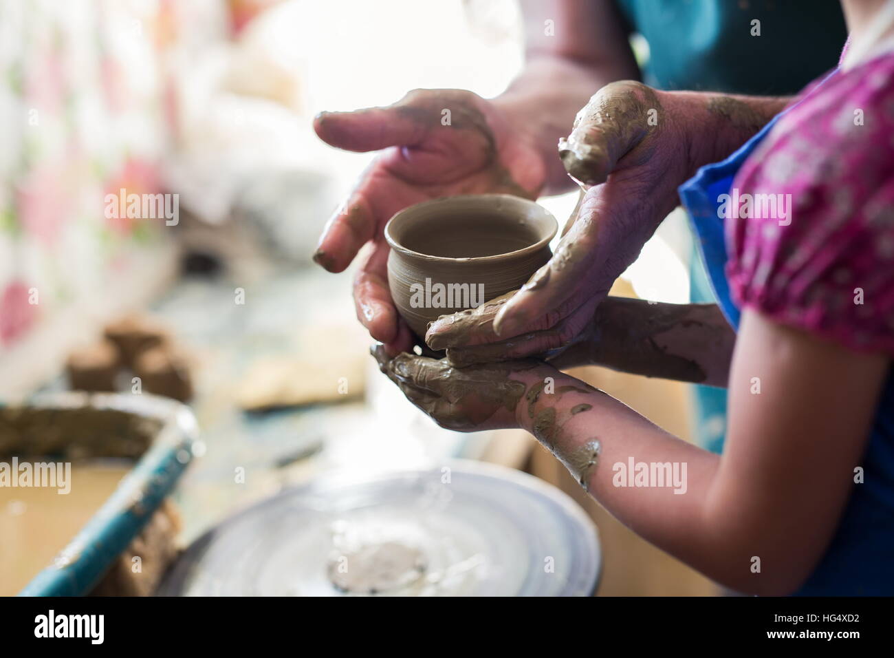 Senior potter teaching a little girl the art of pottery. Child working ...