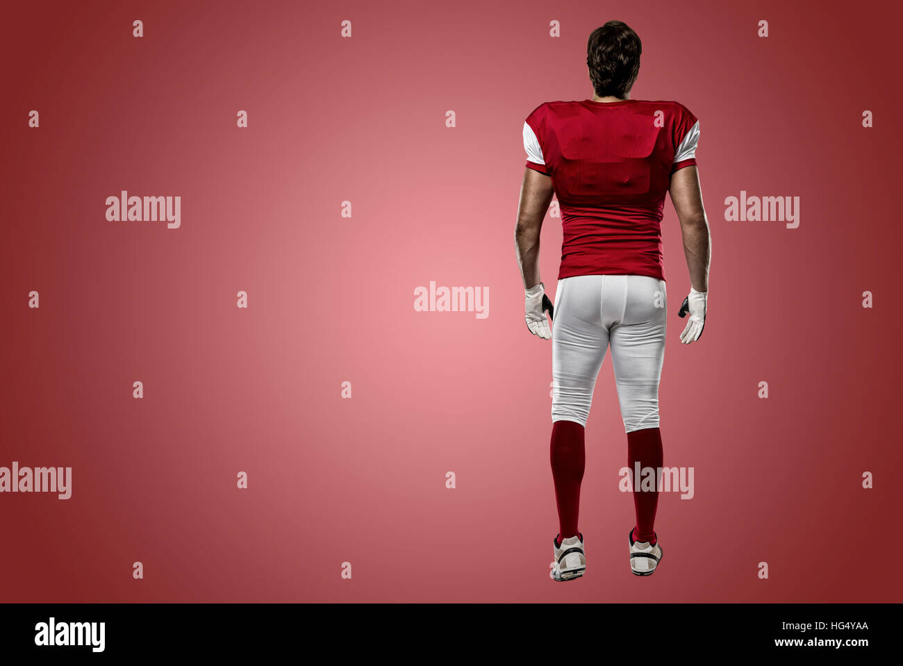 Football Player with a red uniform walking, showing his back on a red ...