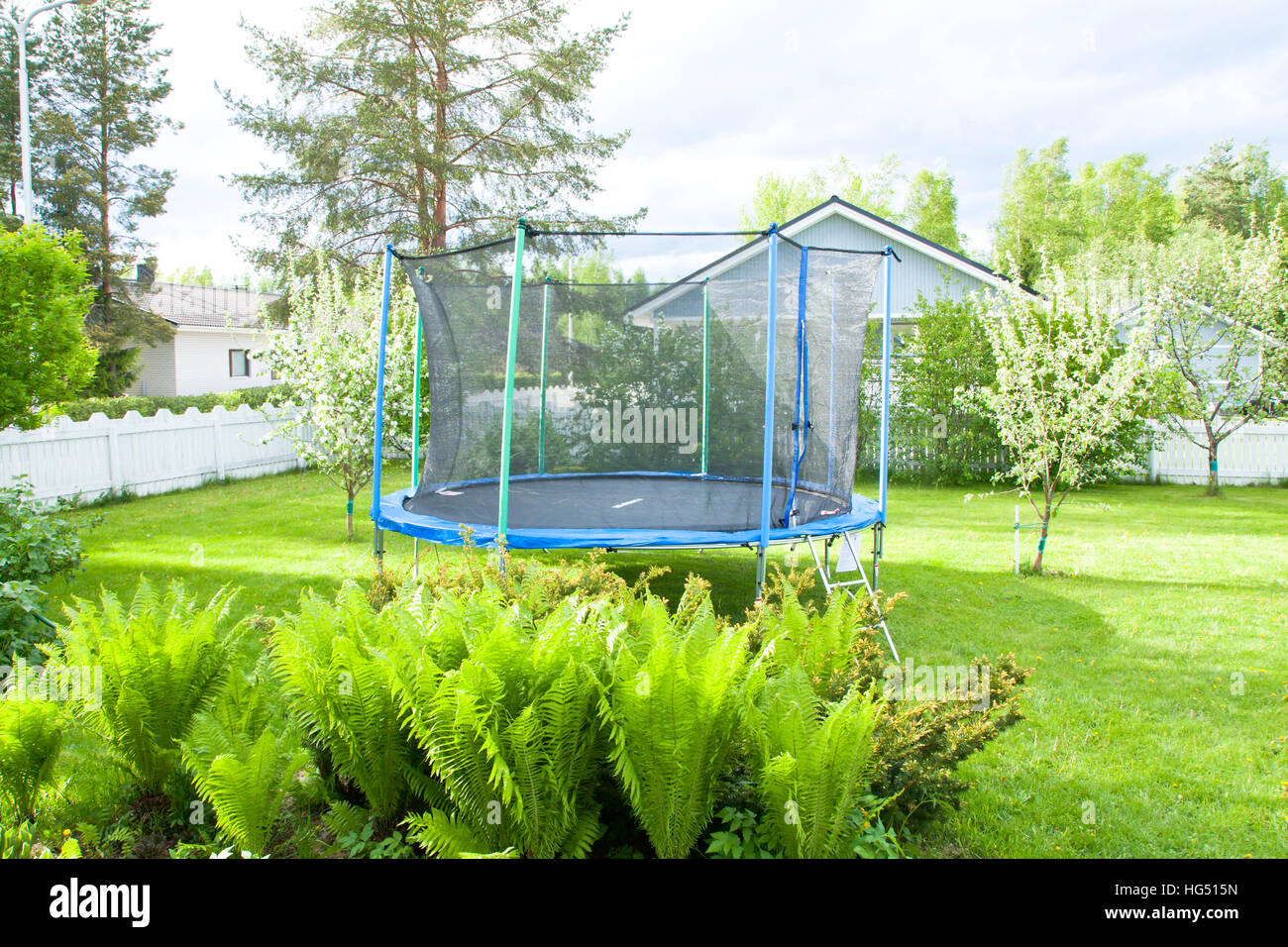 Blue trampoline on the lawn in the garden Stock Photo - Alamy