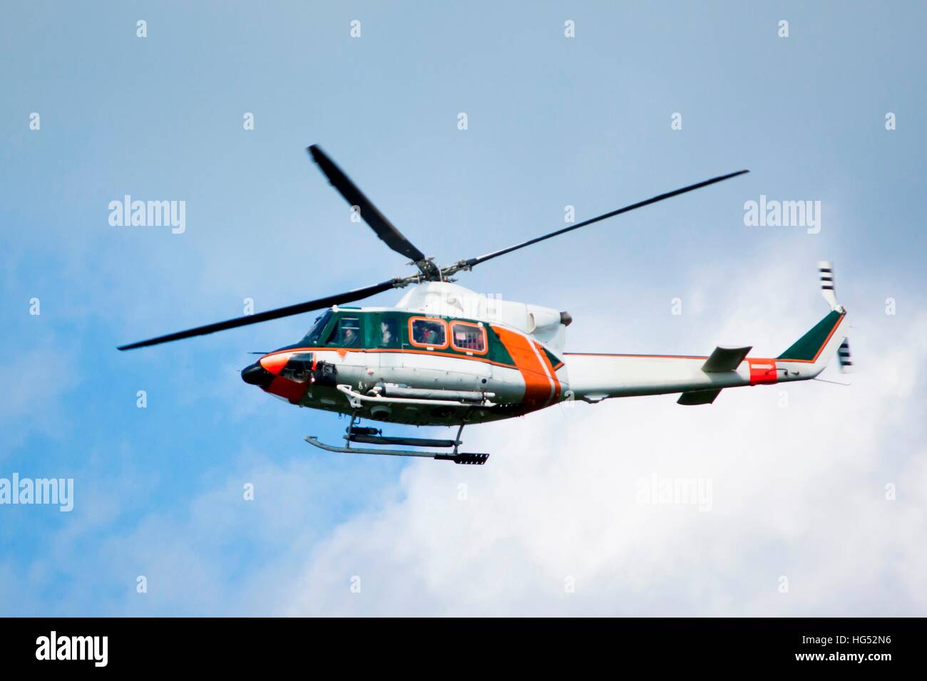 White-orange helicopter is flying in blue sky Stock Photo - Alamy