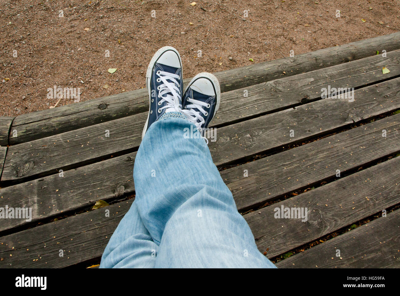 feet in blue sneakers and jeans on a wooden bench Stock Photo - Alamy