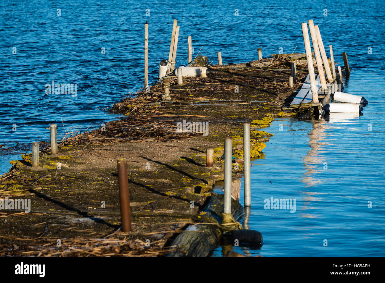 Almost submerged concrete pier with lots of mooring poles in calm water ...