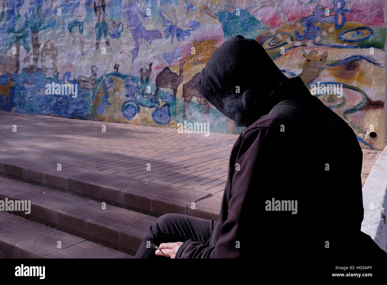 An Israeli man smoking next to a painted wall in Mitzpe Ramon a town in ...