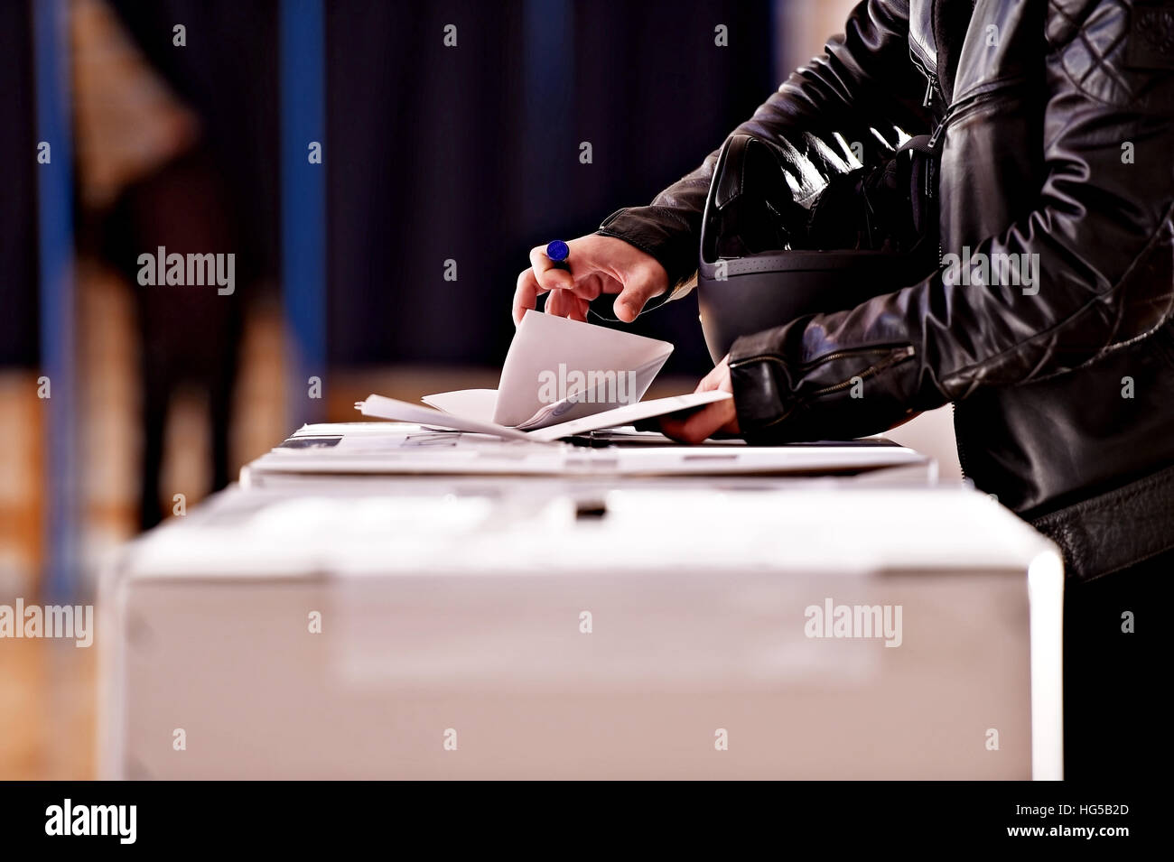 Hands holding a stamp casting a vote into the ballot box during ...