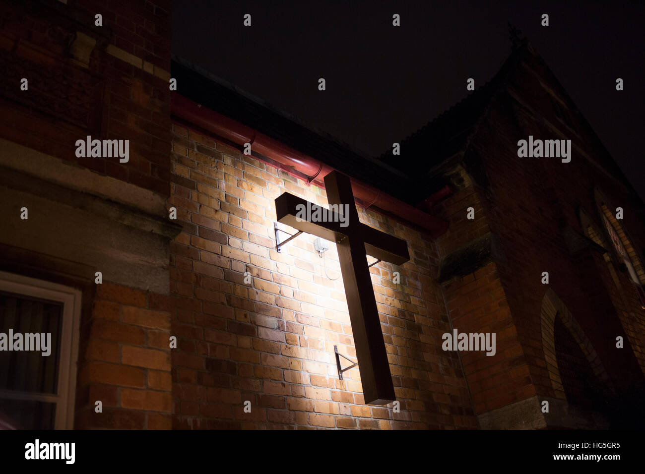 Looking up at an illuminated cross on the wall of a town church Stock ...