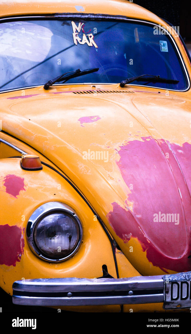 An old rusty car with purple stains over its original yellow color ...