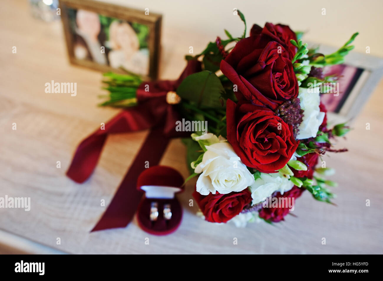 Wedding bouquet of red and white rose and ribbon with wedding rings on ...