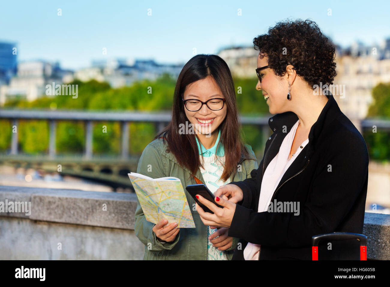 Women tourists holding a paper map and smart phone Stock Photo - Alamy