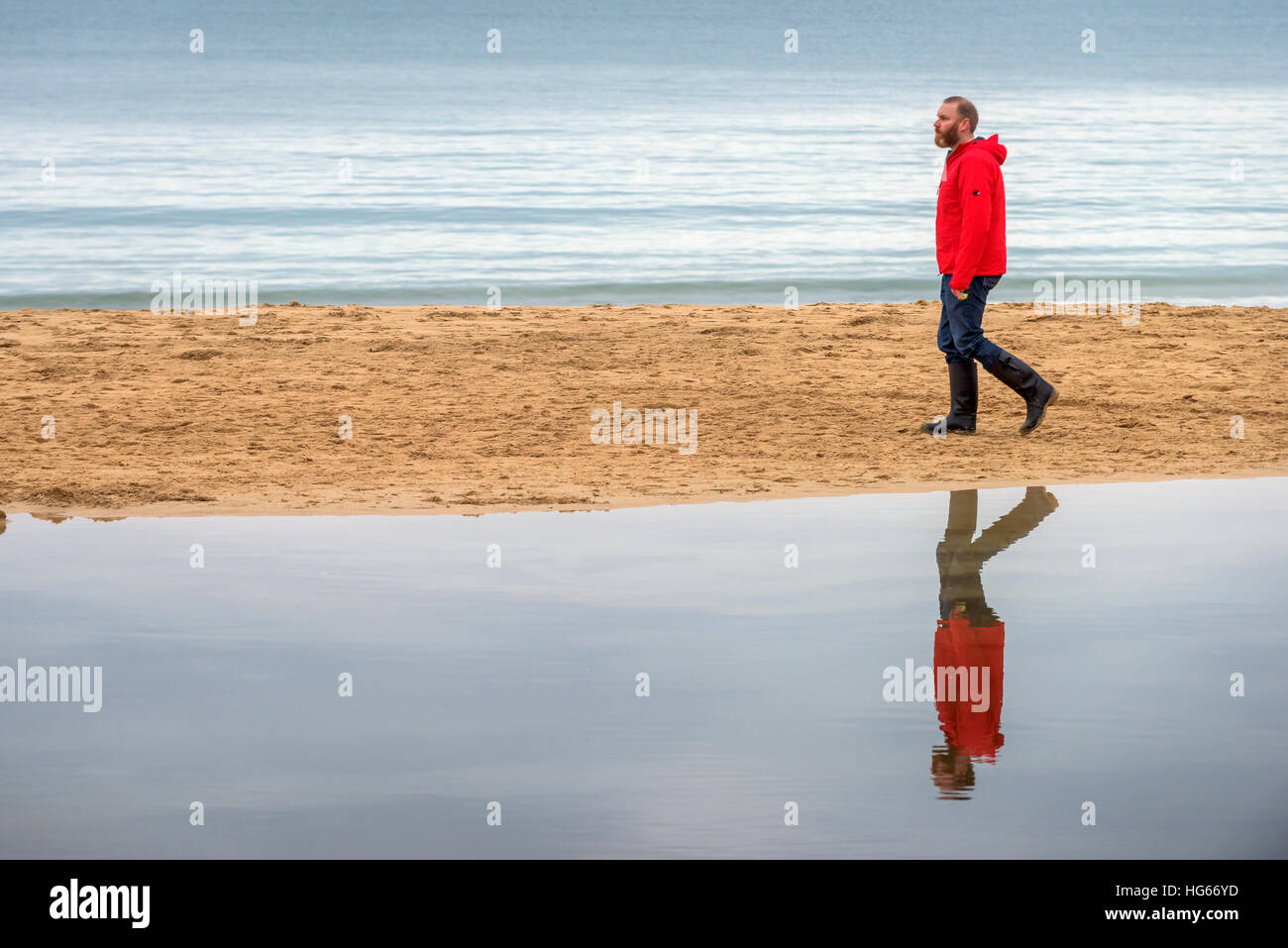 A walker reflected in a pool of water on the beach in Cornwall Stock ...