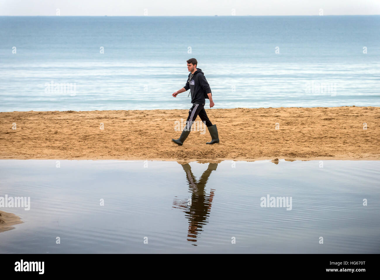 A walker reflected in a pool of water on the beach in Cornwall Stock ...