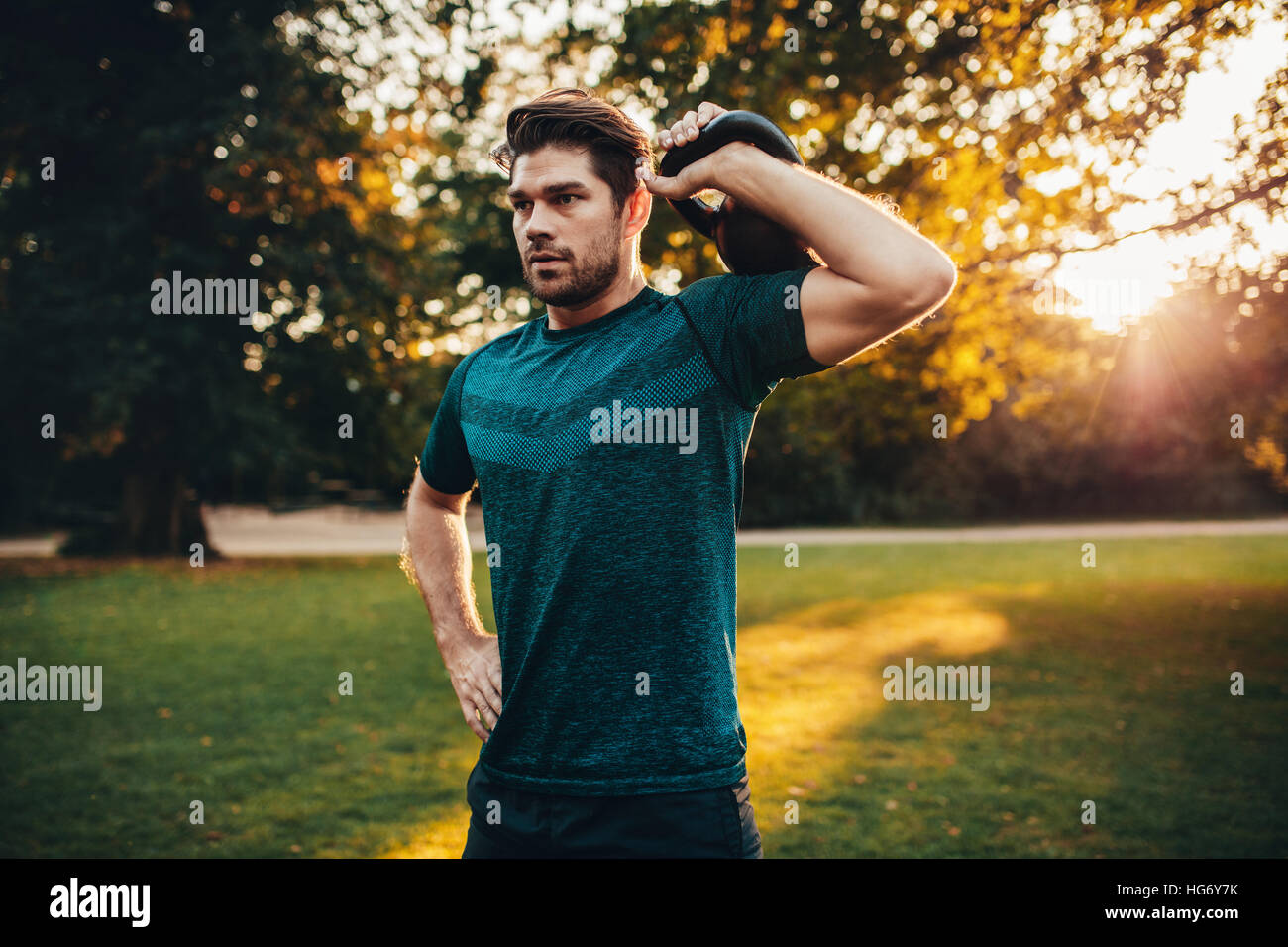 Portrait of tough young guy exercising with kettlebell in park. Fit man ...