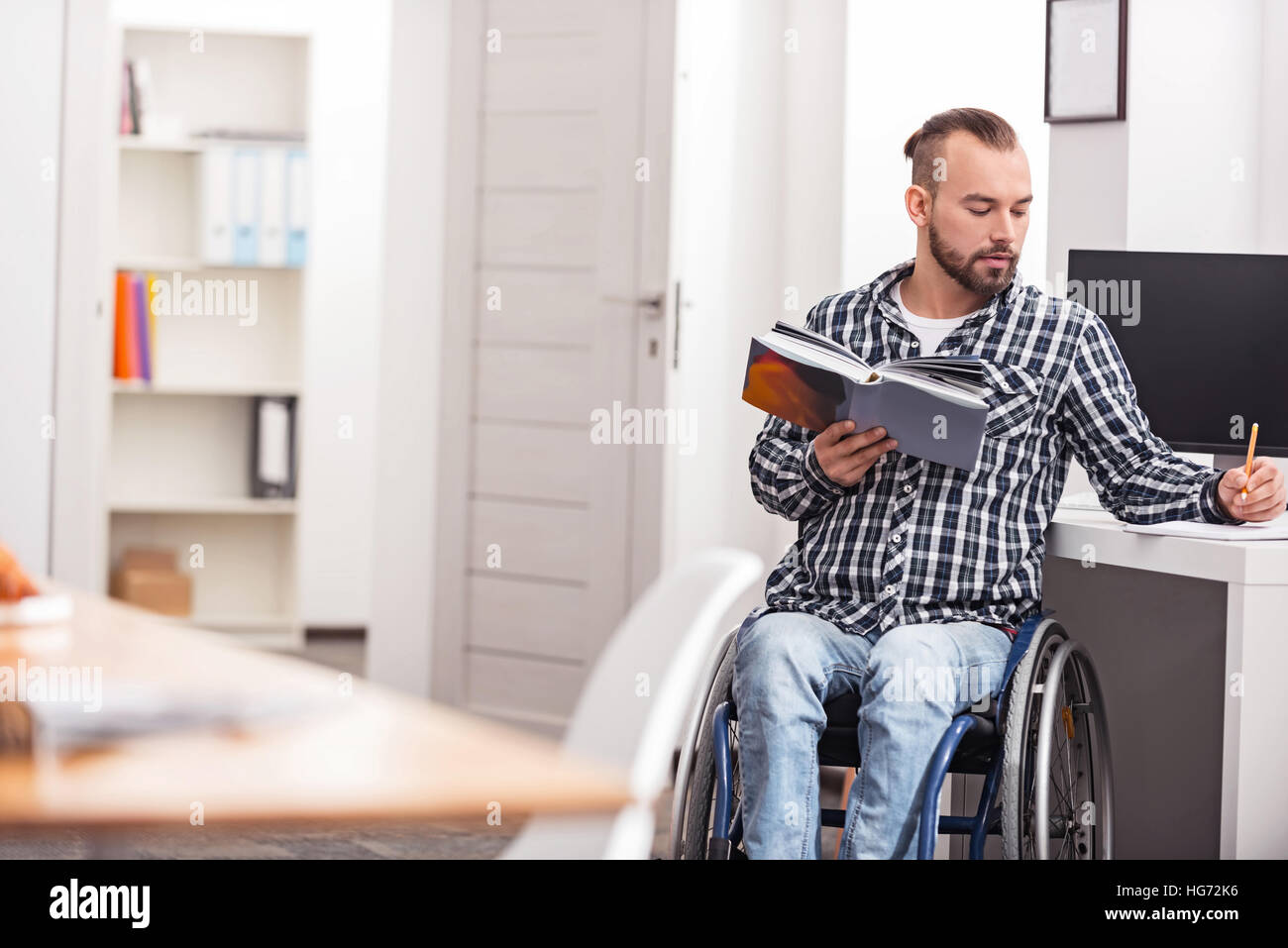 Smart disabled guy spending his free time studying Stock Photo - Alamy