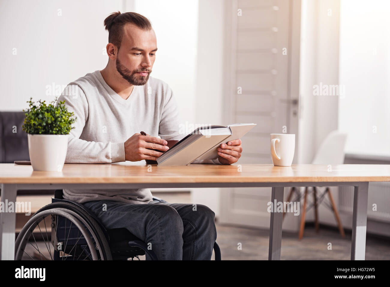 Smart disabled guy reading during breakfast Stock Photo - Alamy