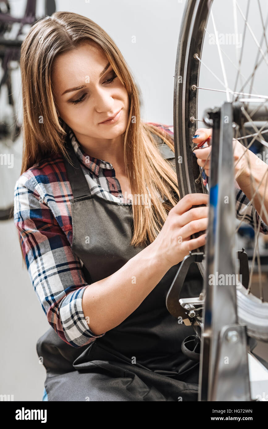 Positive woman repairing the wheel bicycle in the repair shop Stock ...