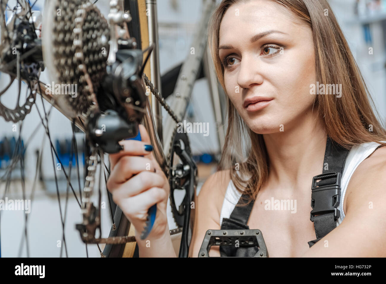 Attractive female mechanic fixing the chain of the bicycle Stock Photo ...